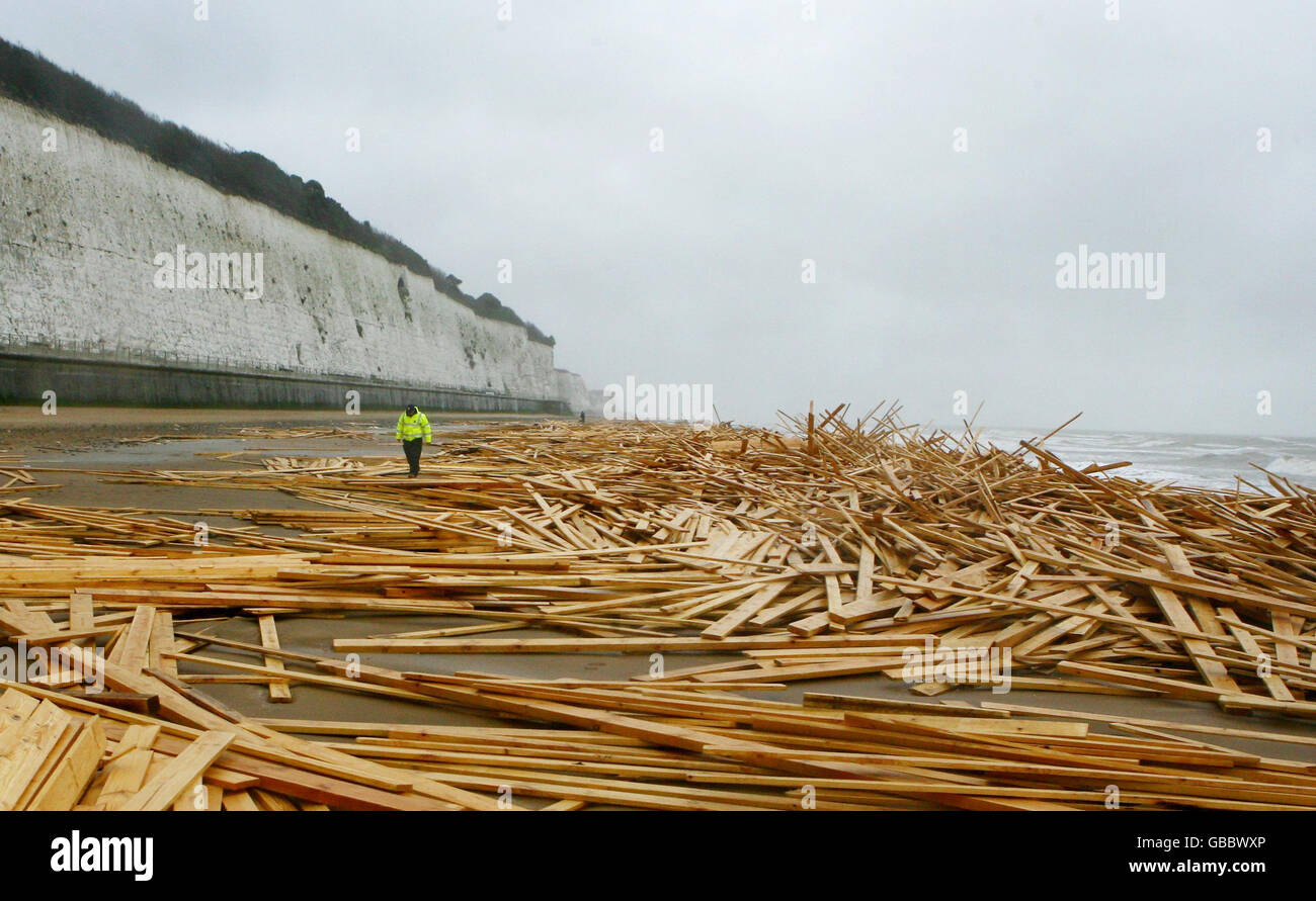Washed up Timber. A beach supervisor walks past timber washed up in ...