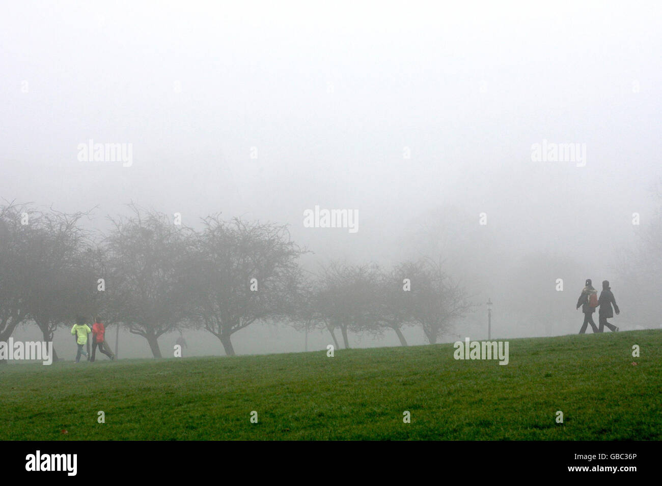 Joggers and people walking in heavy fog on Primrose Hill in north ...