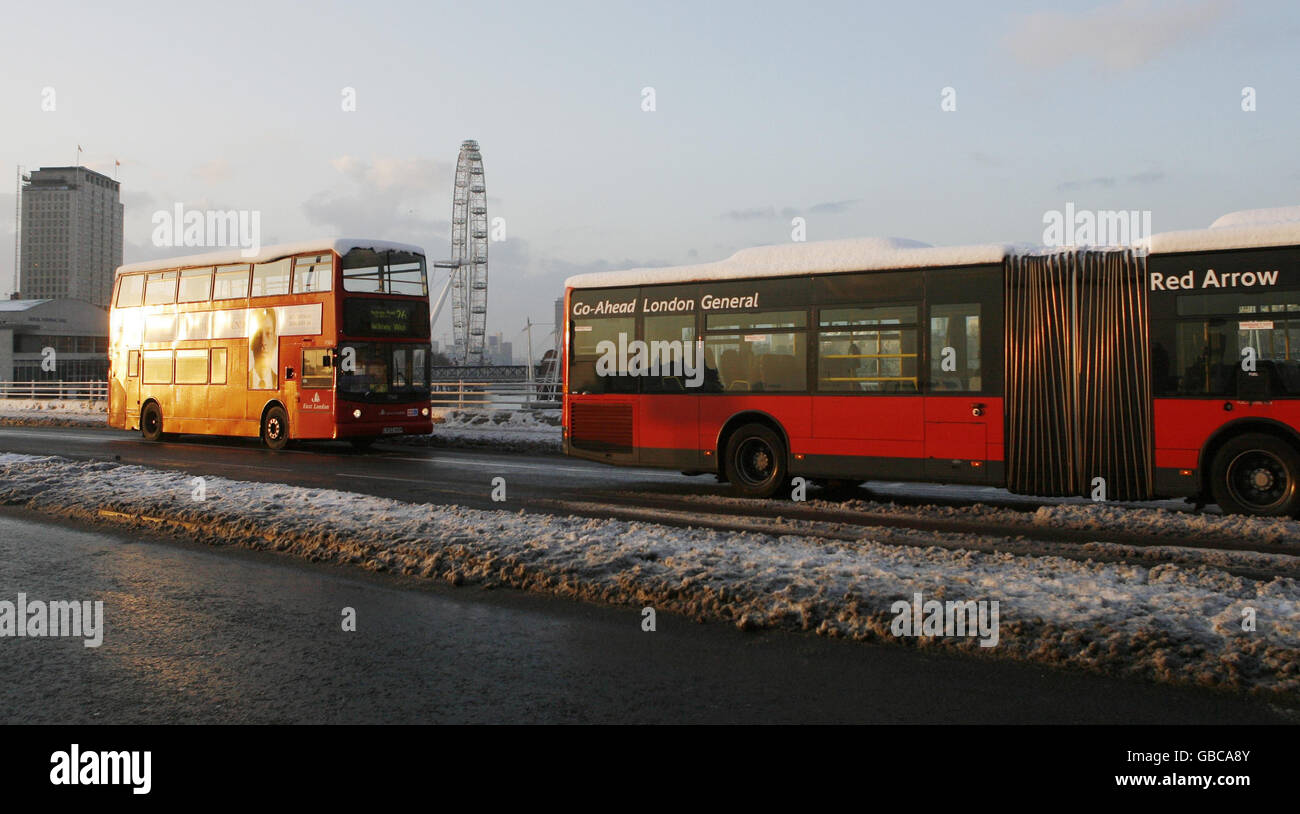 Snow-capped buses cross Waterloo Bridge in central London, the day ...