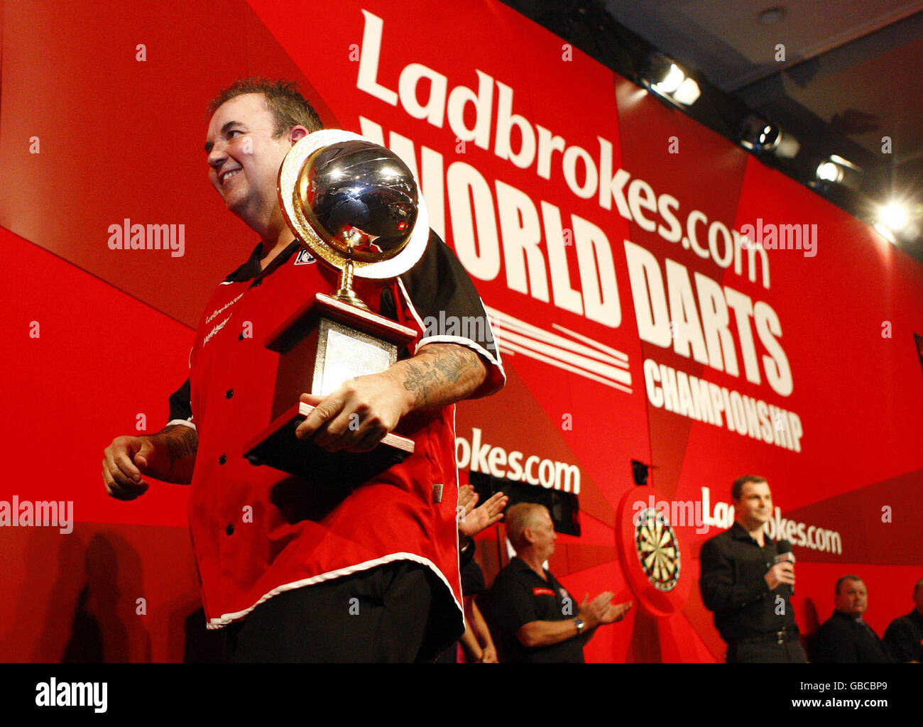 Champion Phil Taylor walks off the stage with the winners trophy under ...