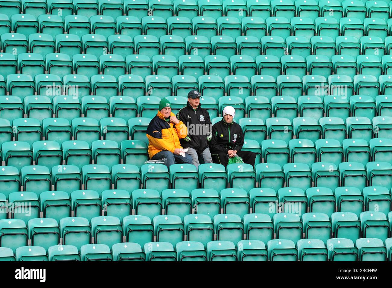 Three Hibernian fans sit alone in the stands as they await kick off ...