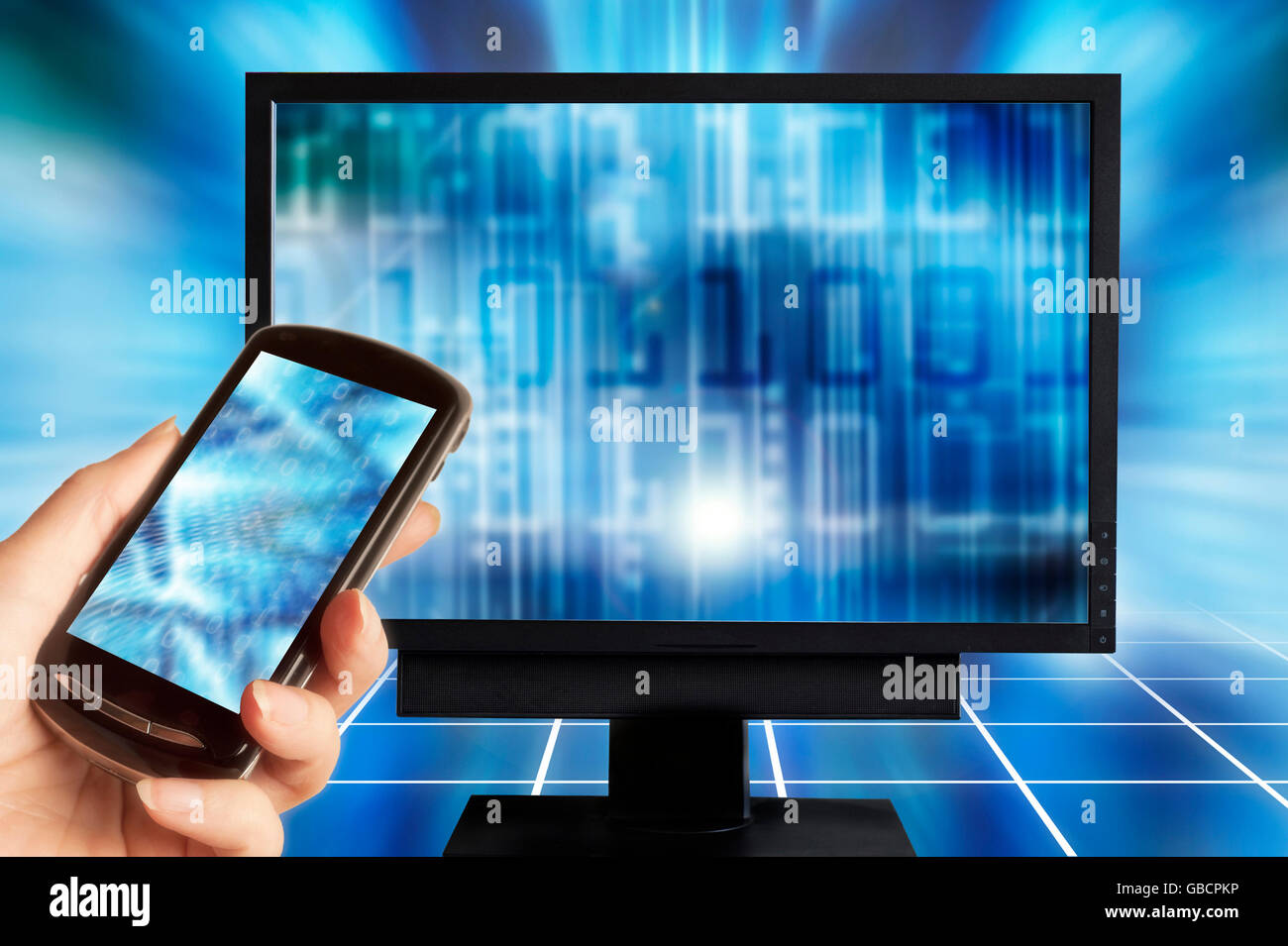 hand holding cell phone in front of a computer monitor Stock Photo - Alamy