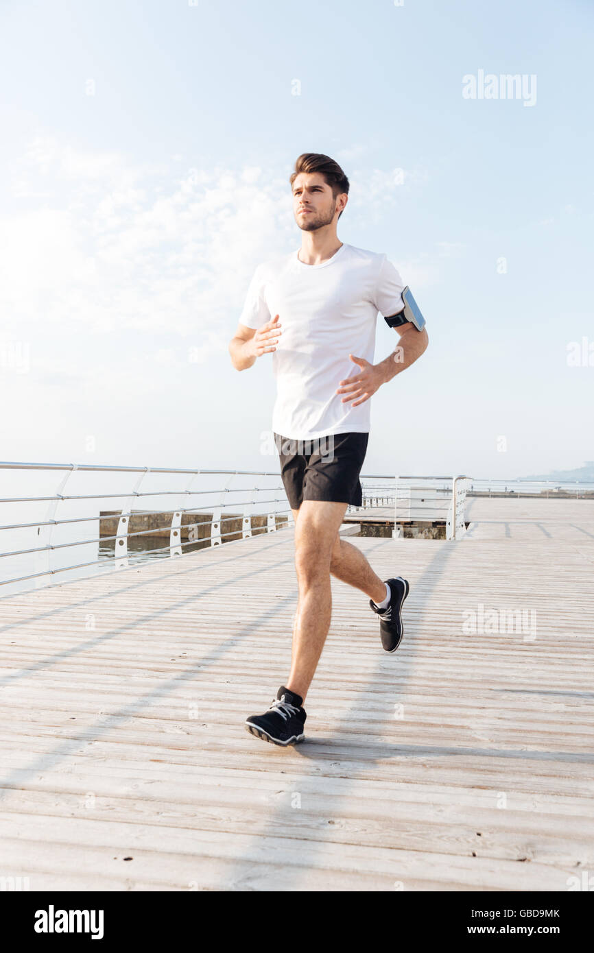 Attractive young man athlete running on wooden terrace Stock Photo - Alamy