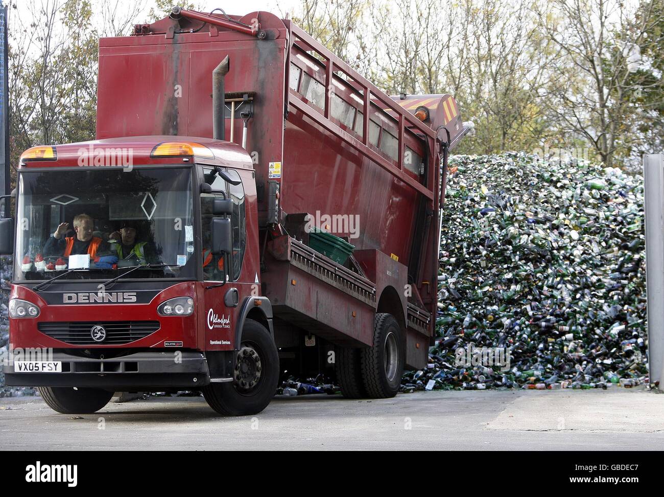 General view of a Dennis refuge lorry dumping glass bottle on a pile ...