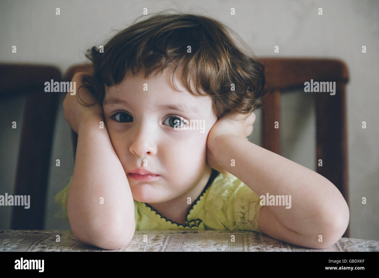 sad girl sits at a table with her hands on face Stock Photo - Alamy