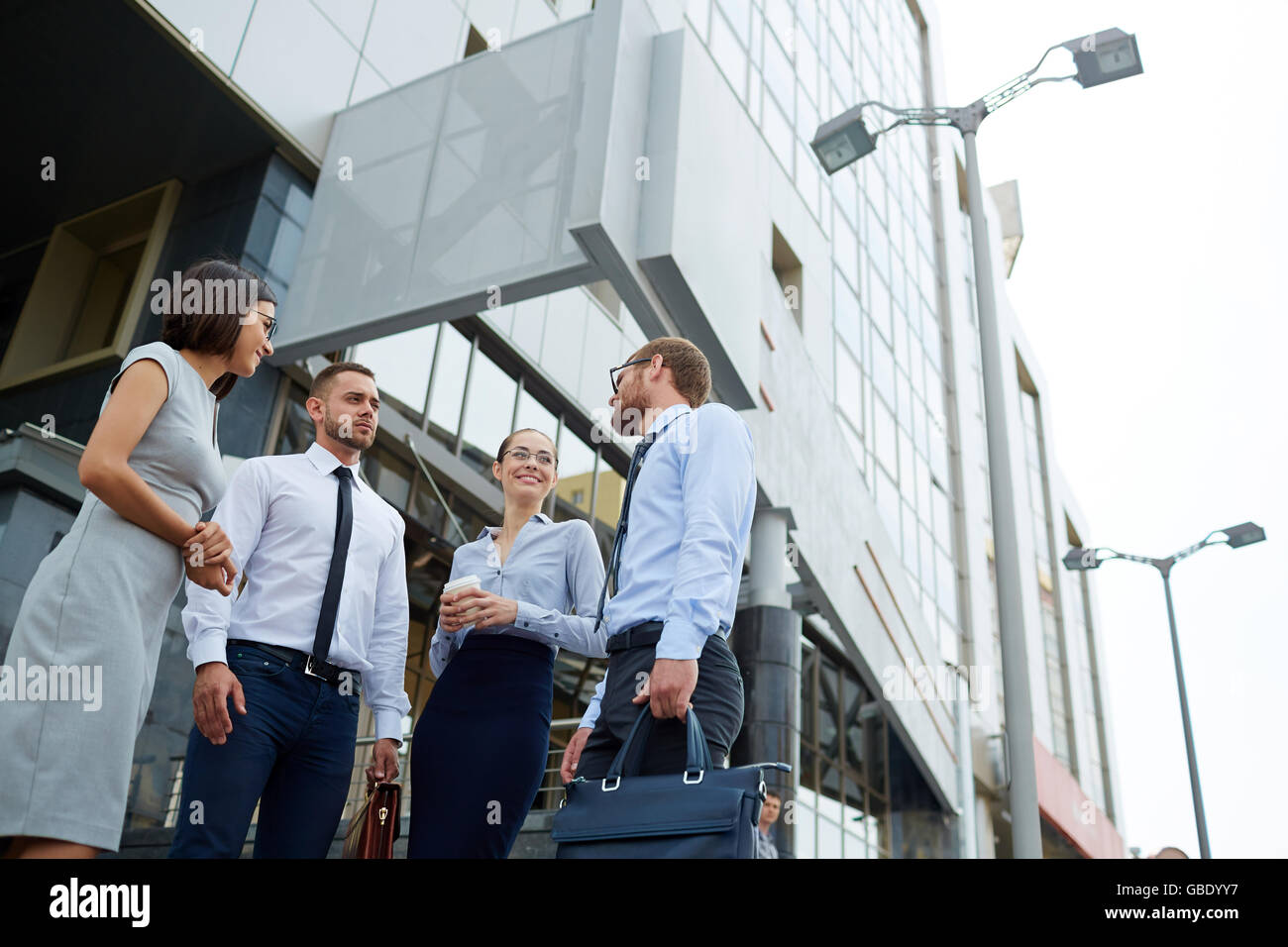Group of young employees having meeting by office building Stock Photo ...