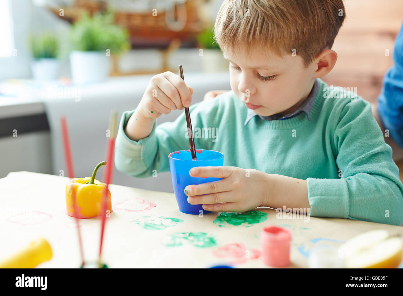 Little boy painting peer with gouache to make prints Stock Photo - Alamy