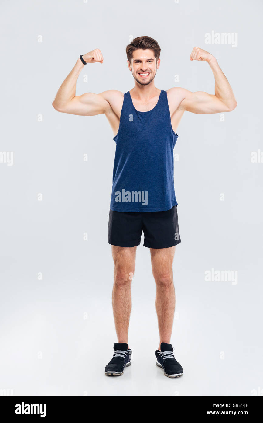 Full length portrait of a smiling man showing his biceps isolated on a ...
