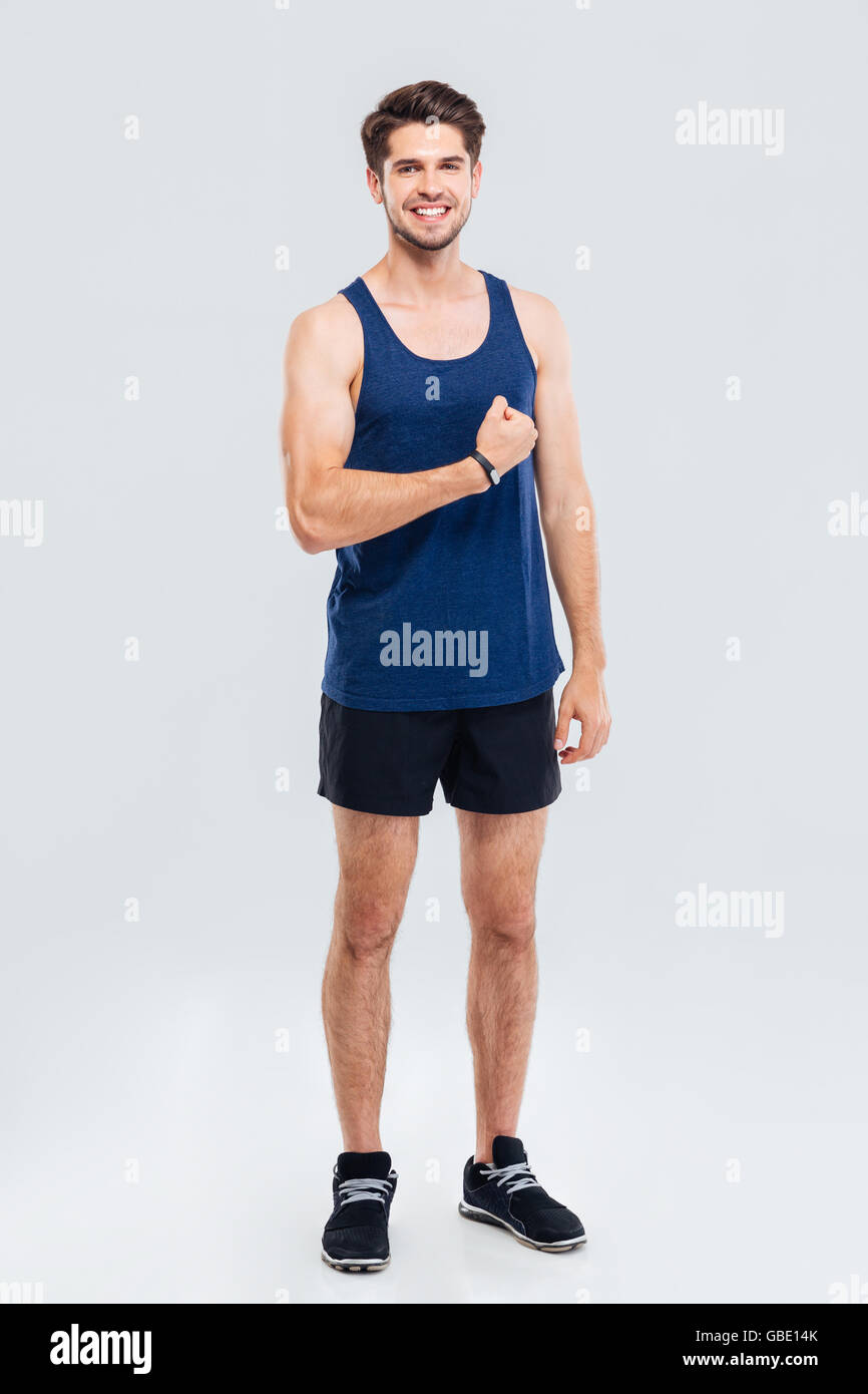 Full length portrait of a smiling man showing his biceps isolated on a ...