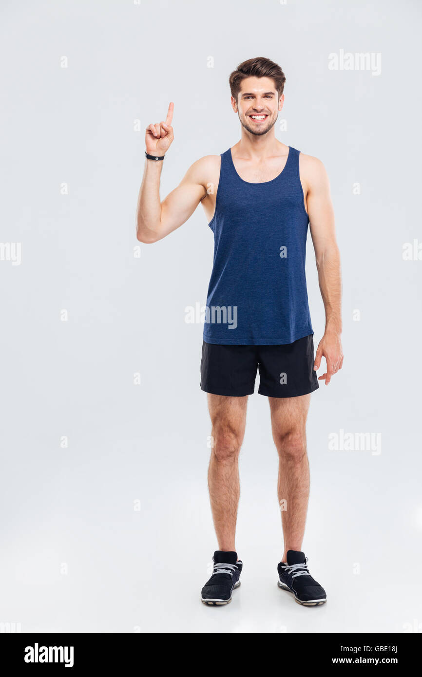 Full length portrait of a smiling sports man showing up on something ...