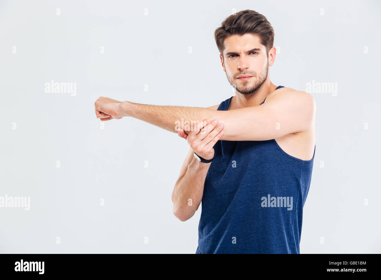 Handsome young sportsman stretching hands during workout isolated on a ...