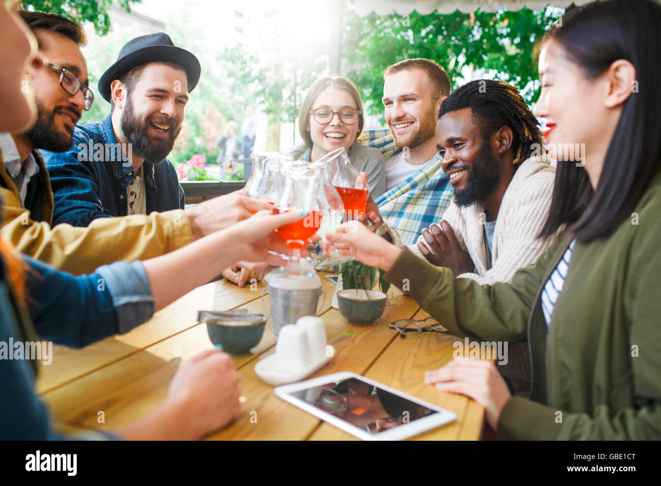 Happy intercultural friendly young people toasting with drinks in ...
