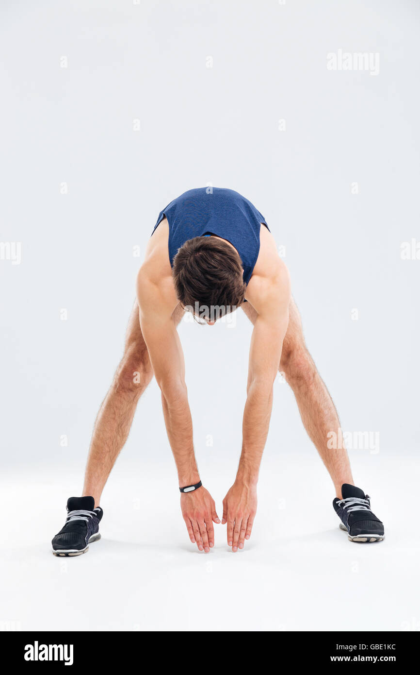 Full length of athletic young man training and doing stretching ...