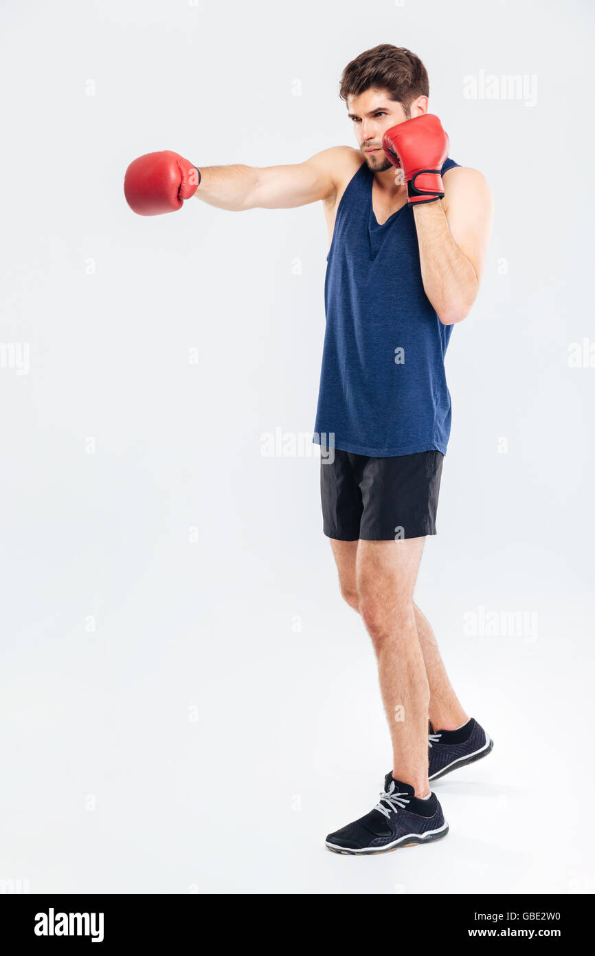 Full length portrait of a young handsome sports man boxing in red ...