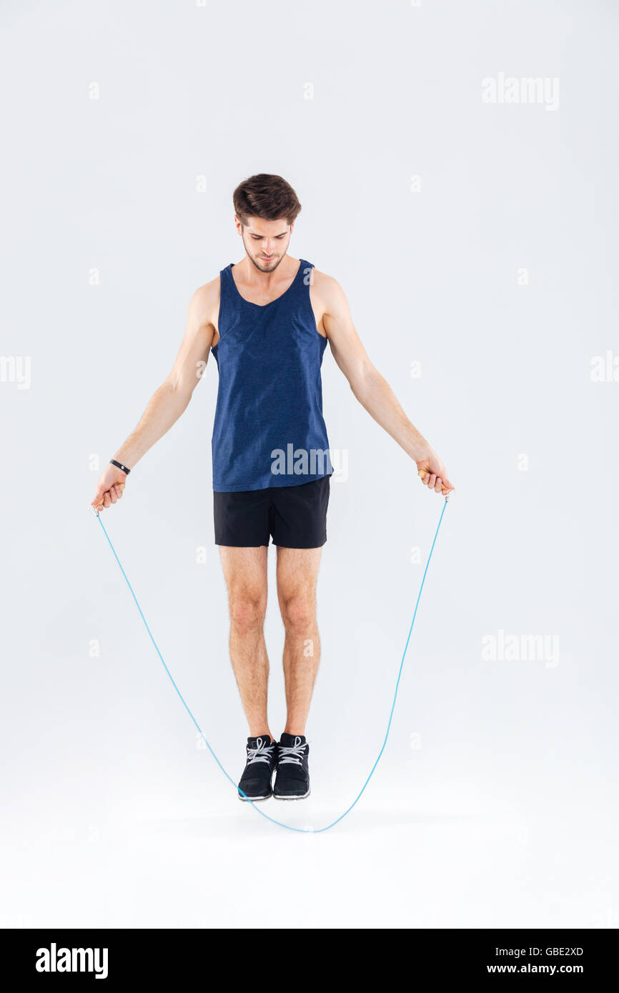 Full length portrait of a man jumping with skipping rope isolated on a ...