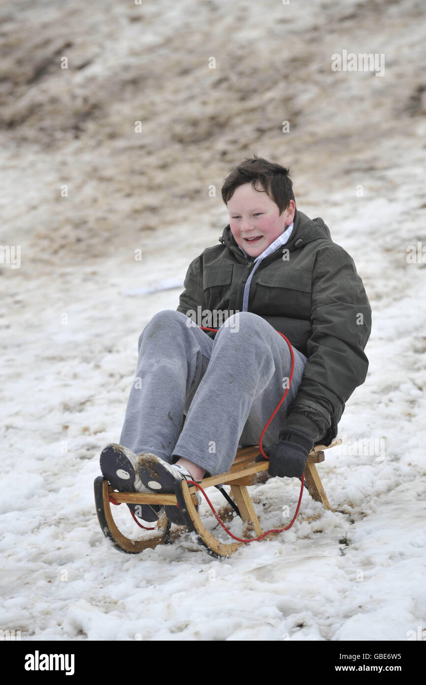 A young lad rides a traditional sledge at Arnos Vale park, Bristol ...