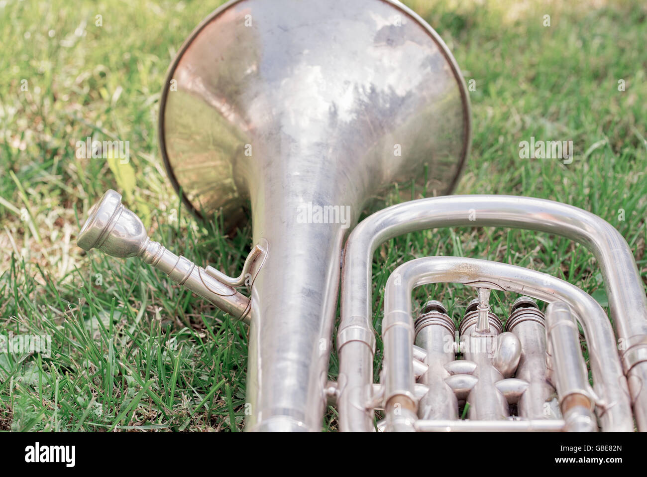 part of silver trombone on th grass, close up image Stock Photo - Alamy