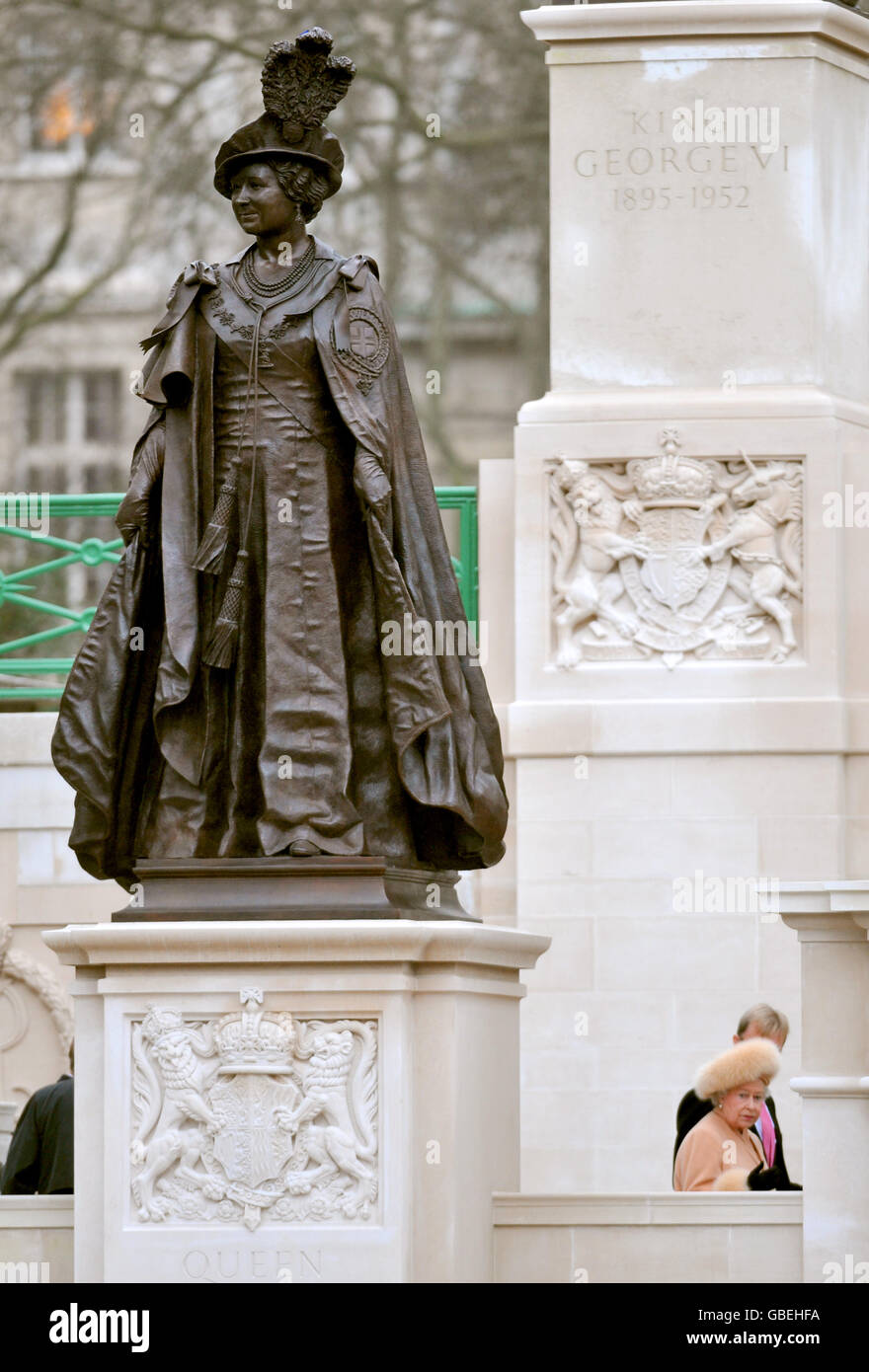 Britain's Queen Elizabeth II (right) walks past a statue of the Queen ...