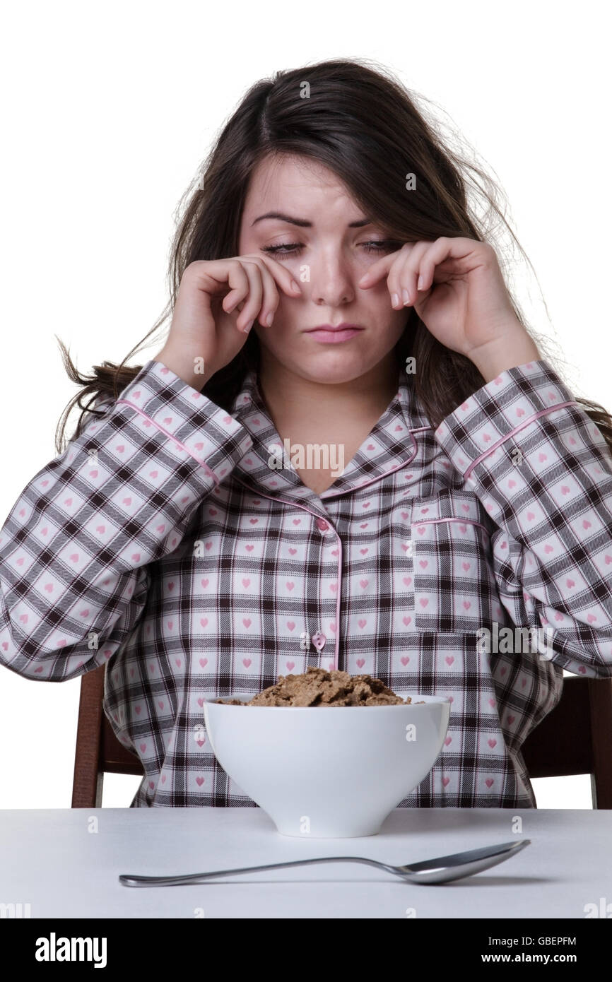 Very tired model, sitting at the breakfast table with a bowl of cereal ...