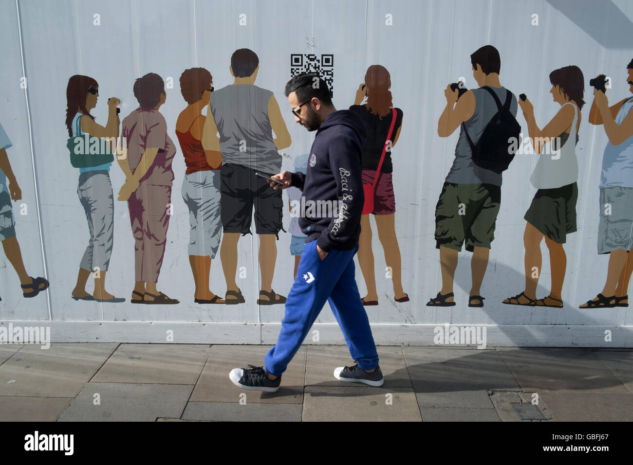Outside a shop under refit a hoarding depicting members of the public ...
