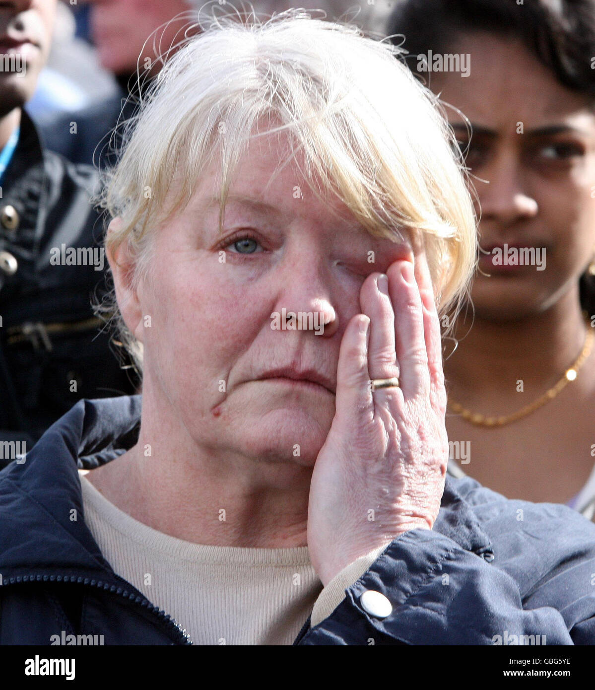 A woman wipes her eye during a prayer service at the scene of a ...