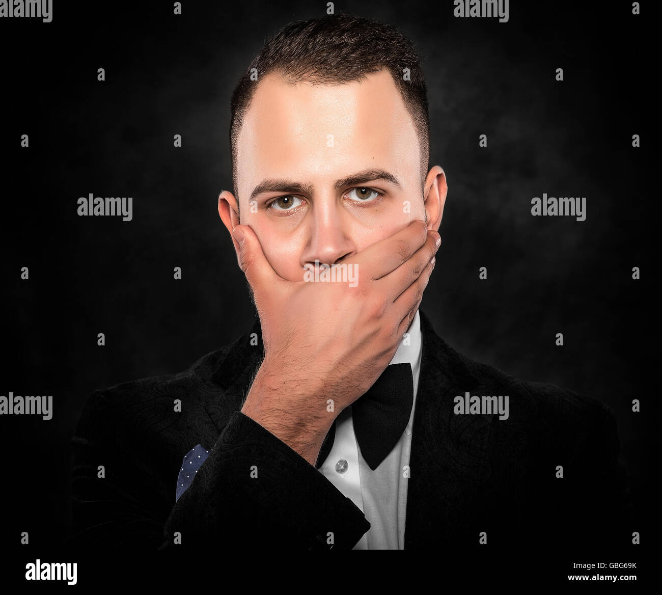 Scared man in suit hand covering mouth over dark background Stock Photo ...