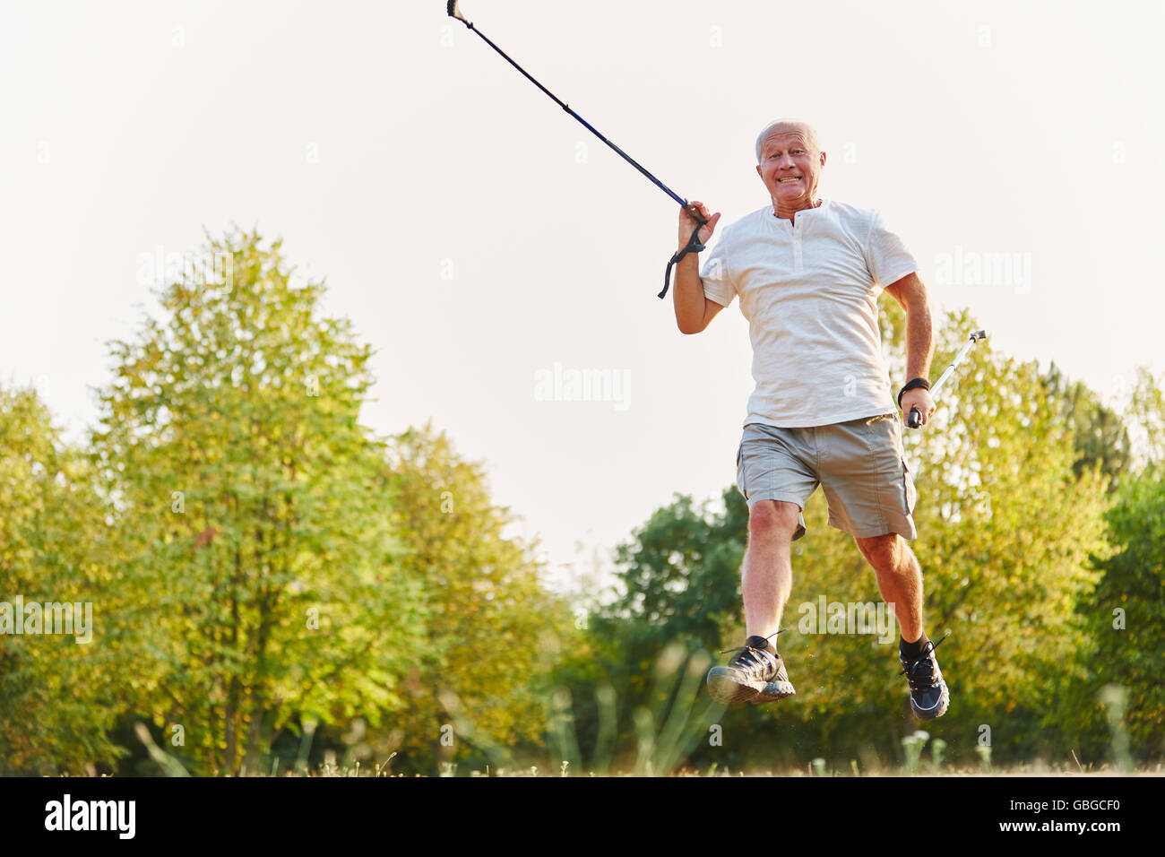 Active senior man jumping during nordic walk in the park Stock Photo ...