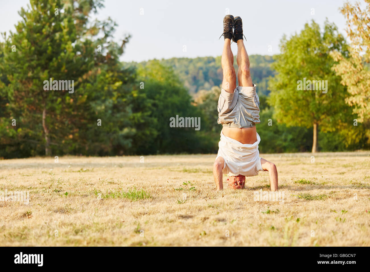 Activ senior man making a headstand in summer in the park Stock Photo ...