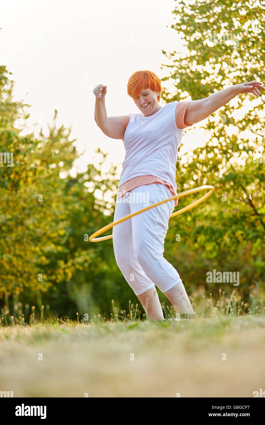 Active senior woman during fitness training in park with a hoop Stock ...