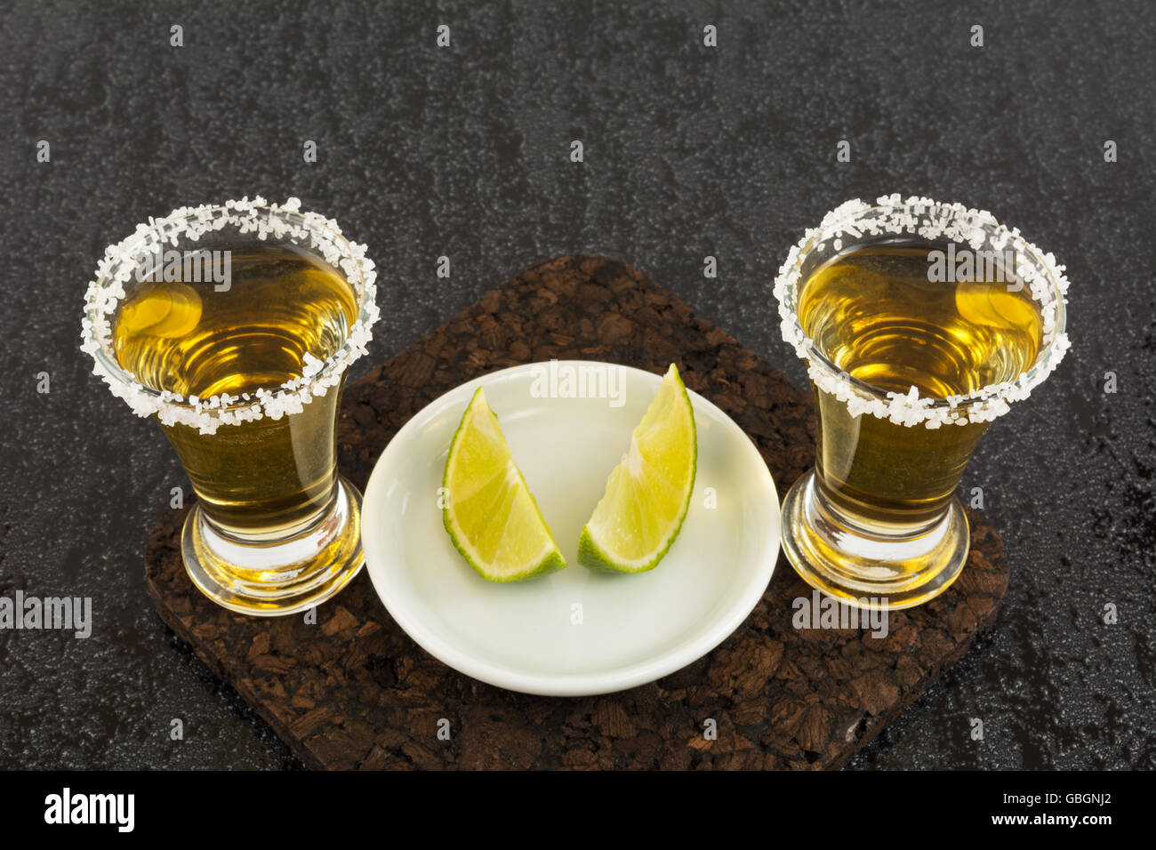 Two gold tequila shots with lime. Tequila shot. Gold Mexican tequila ...
