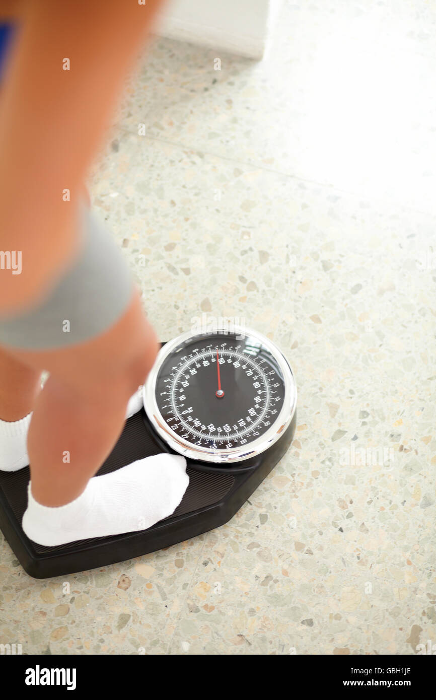 Fit pretty girl weighing herself in a weight scale Stock Photo - Alamy