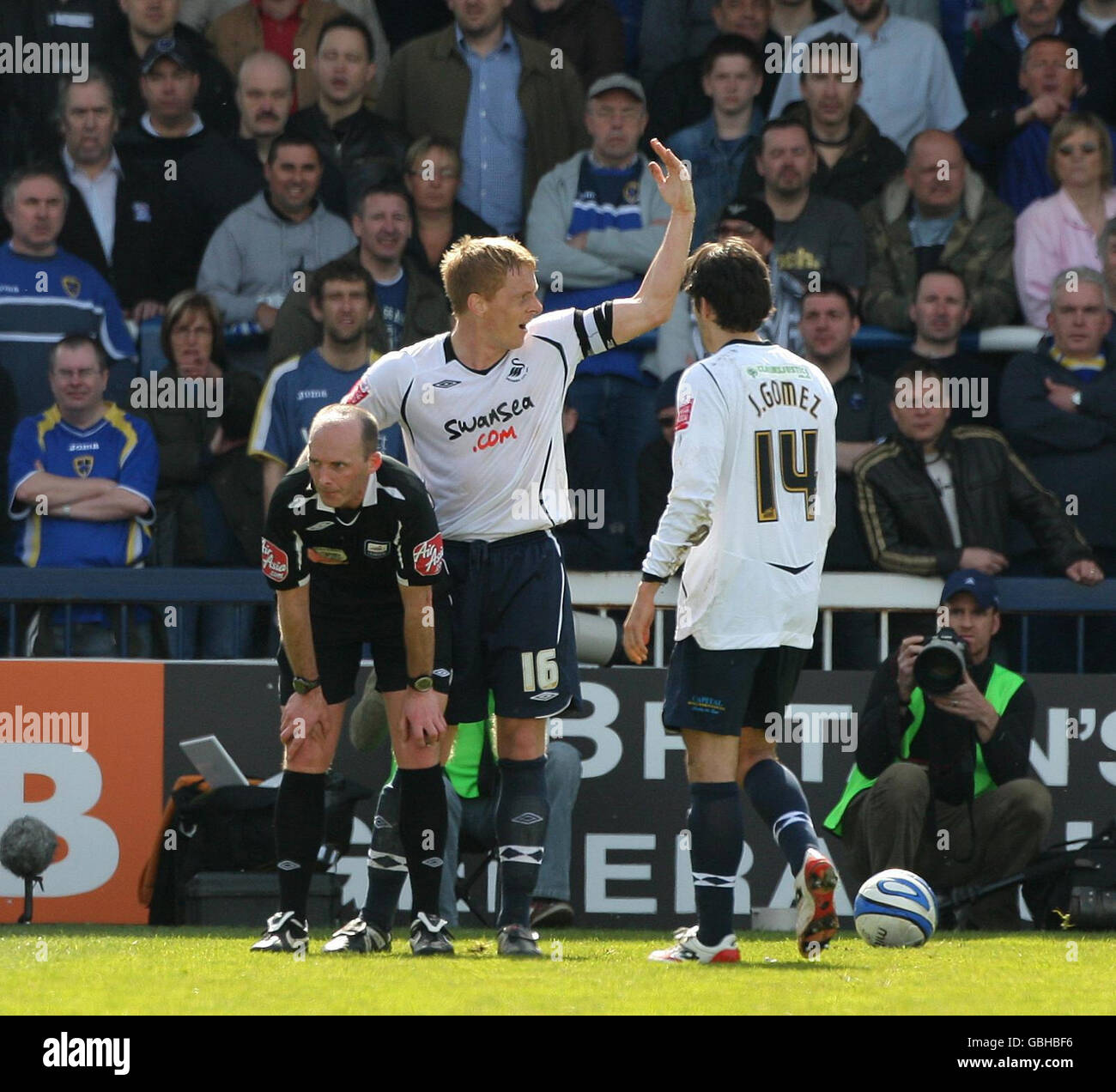 Referee Mike Dean is helped by Swansea City captain Gary Monk after he ...