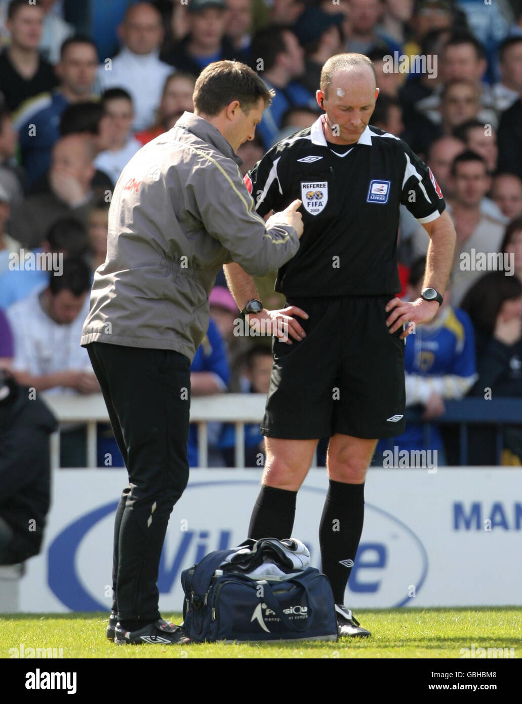Referee Mike Dean is helped by a phyiso after being hit by a coin ...