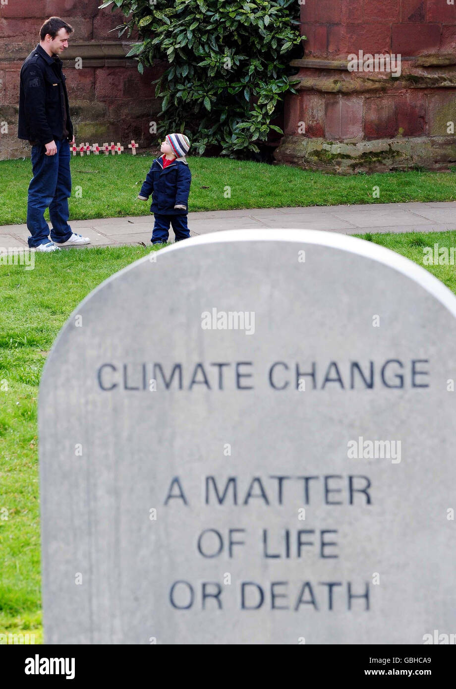 Visitors stands near a mock grave with "Climate Change A Matter Of Life ...