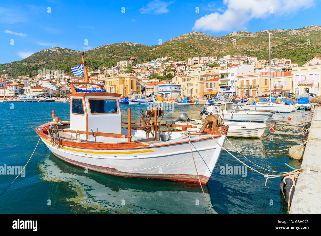 Traditional Greek boat in port of Samos with colourful houses in ...