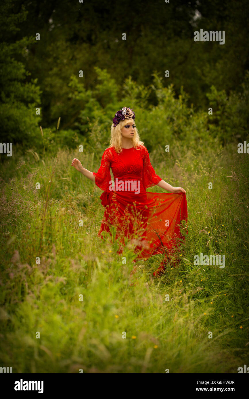 Blonde romantic fairy elf model in meadow with with gold purple rose ...