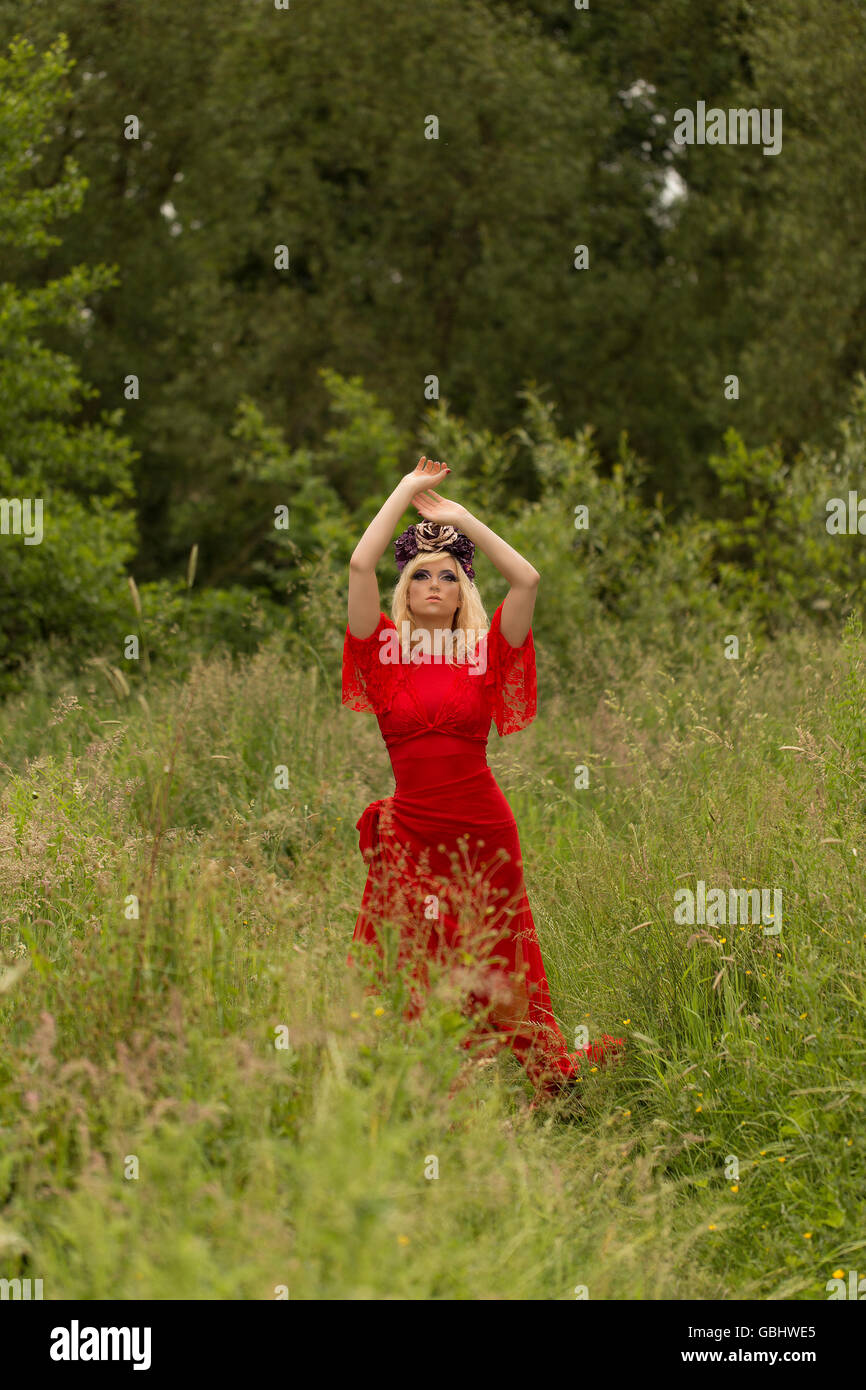 Blonde romantic fairy elf model in meadow with with gold purple rose ...