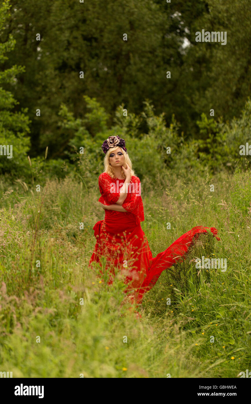 Blonde romantic fairy elf model in meadow with with gold purple rose ...