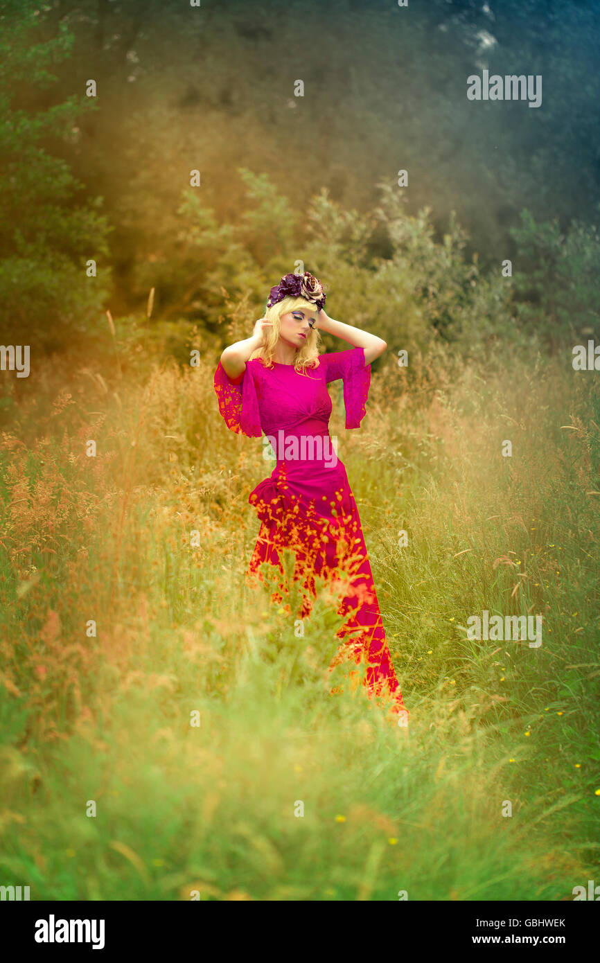 Blonde romantic fairy elf model in meadow with with gold purple rose ...