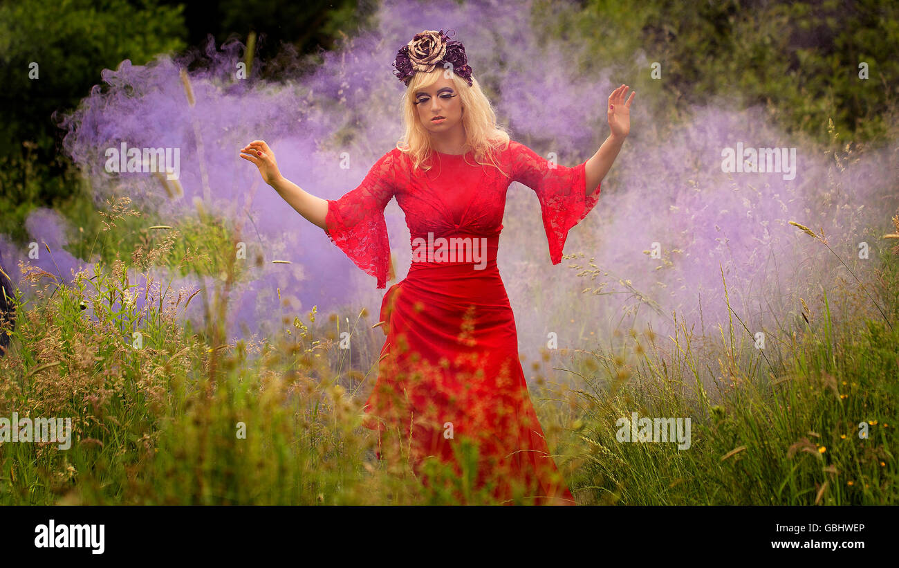 Blonde romantic fairy elf model in meadow with with gold purple rose ...