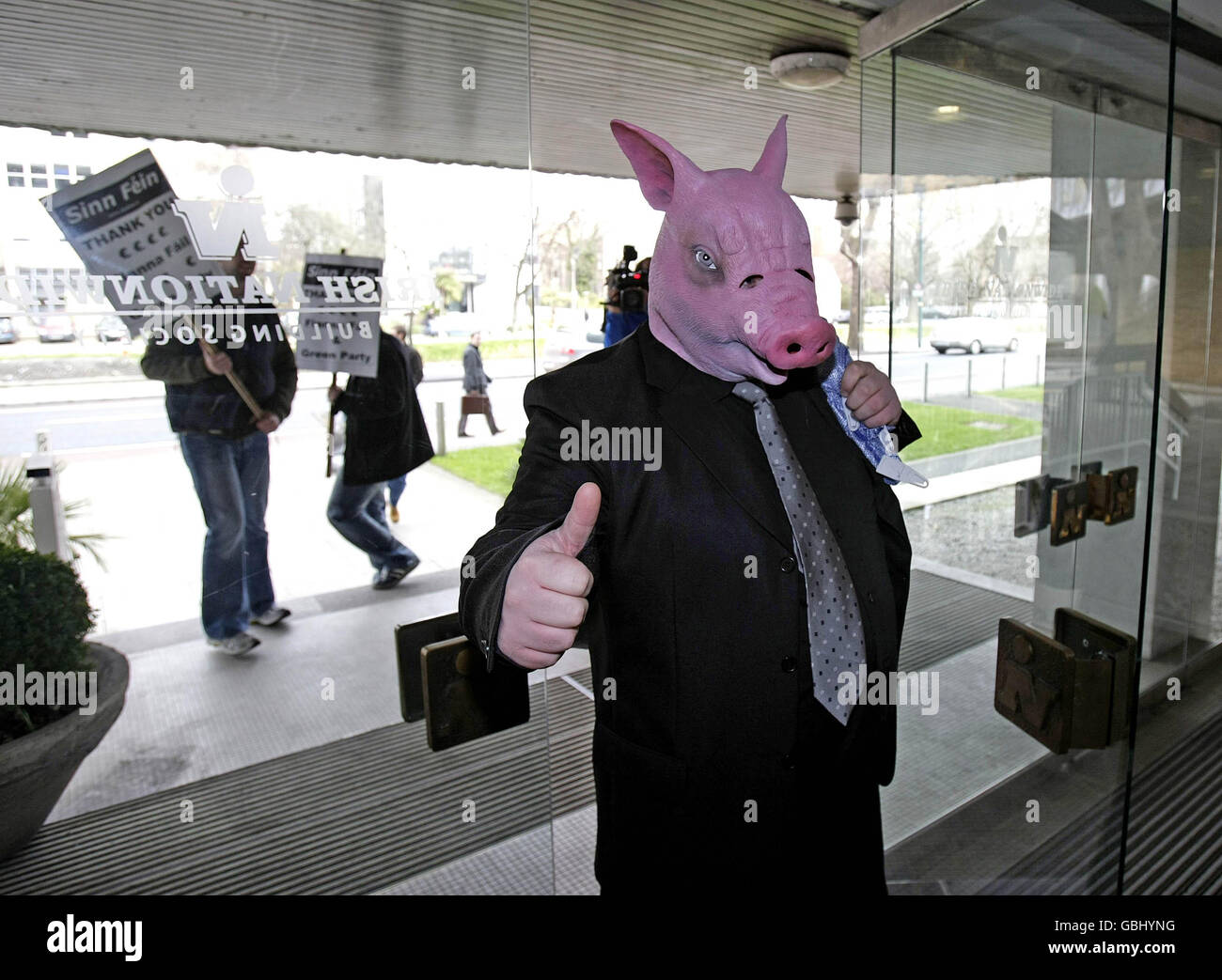 A Sinn Fein activist dressed as a pig carrying bags of money outside ...