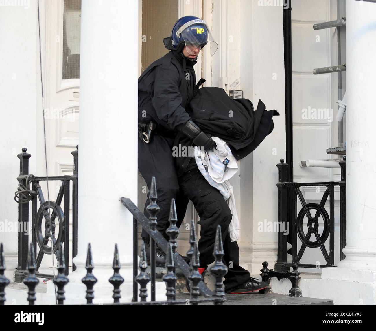 A police officer removes a suspect from a property in west London, part ...