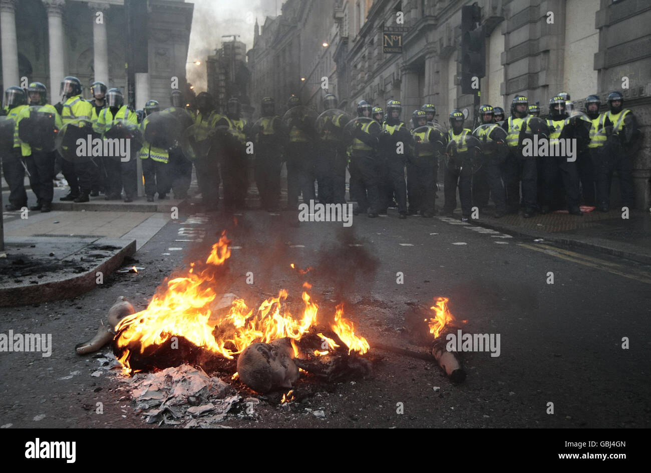 Police officers stand behind a burning mannequin after clashing with ...