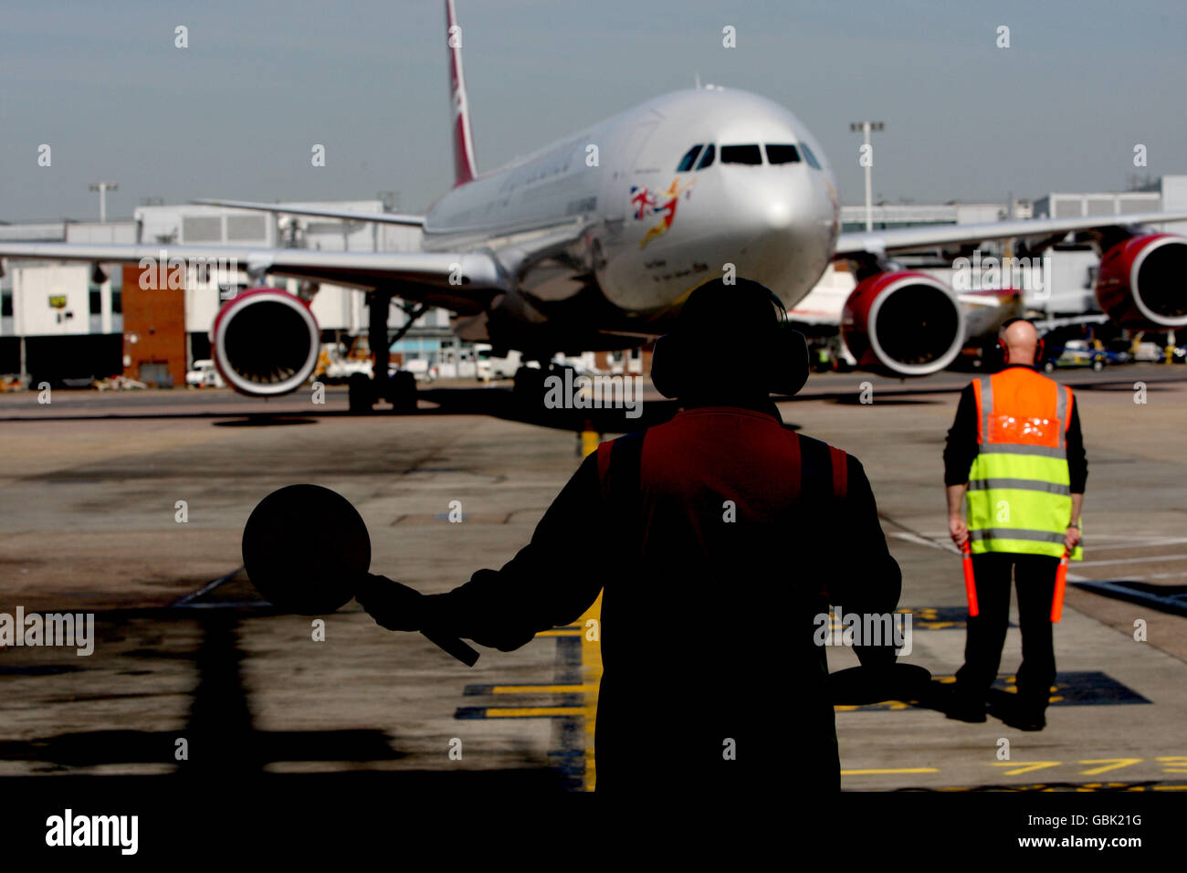 A plane is marshalled onto its stand by a marshaller from the Airside ...