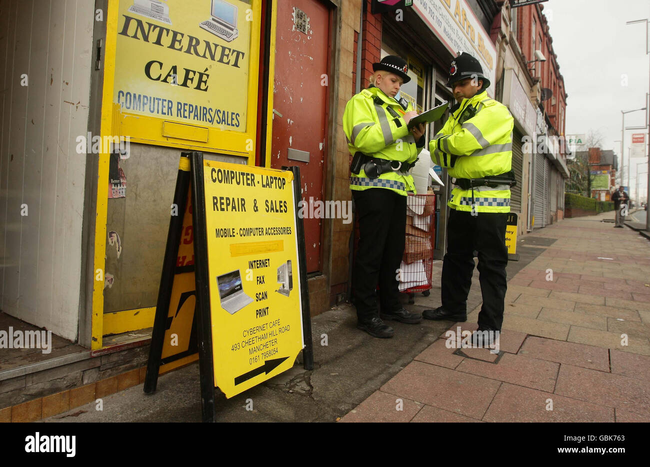 Police officers stand outside an Internet Cafe in the Cheetham Hill ...