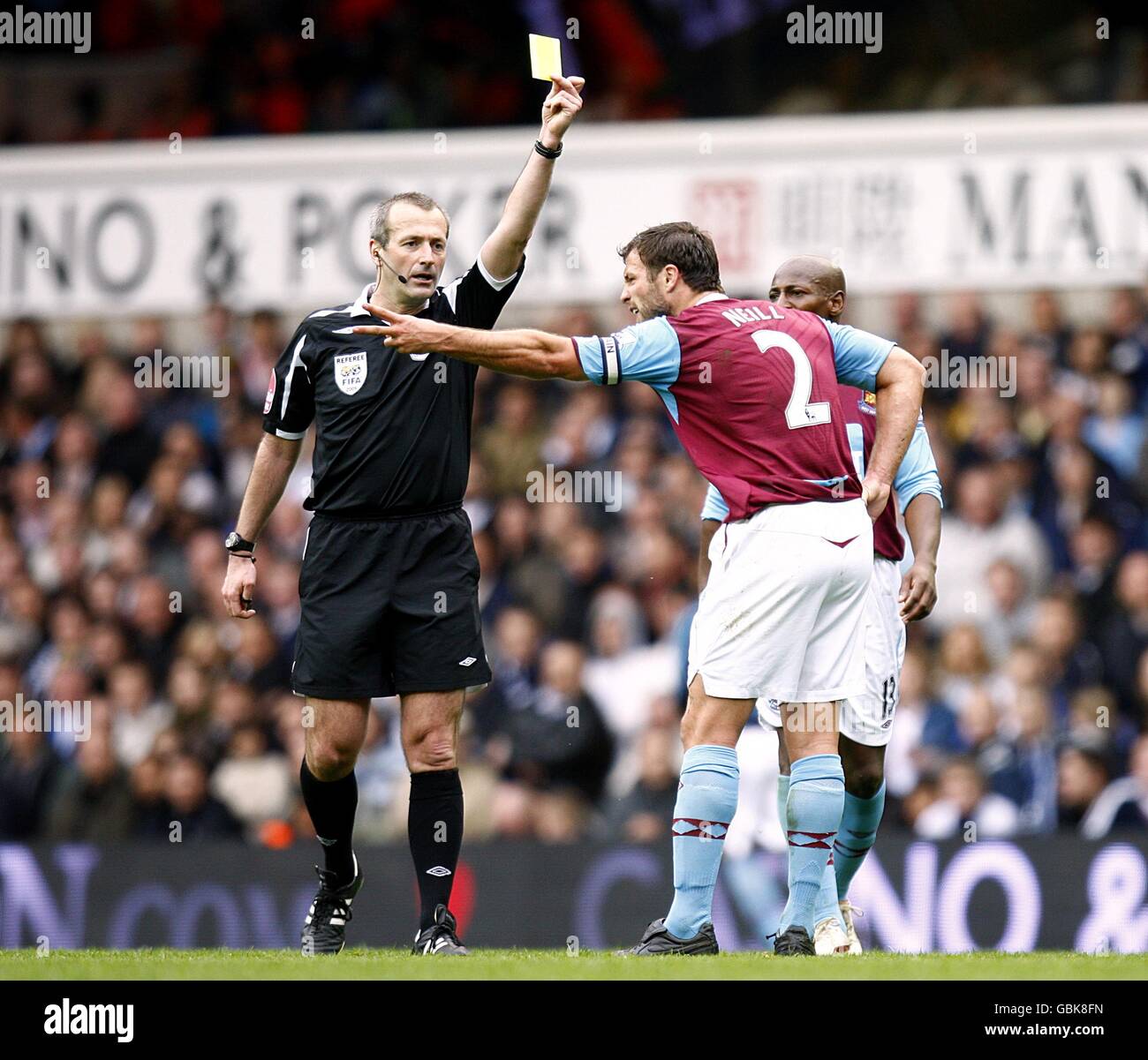 West Ham United's Lucas Neill is booked by referee Martin Atkinson ...
