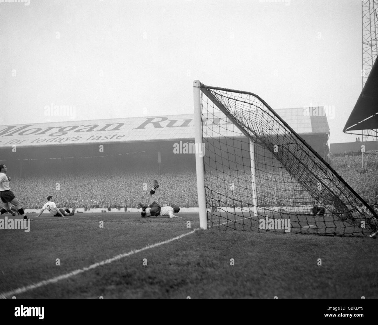 Ron Springett, the England goalkeeper, goes down heavily after making a ...