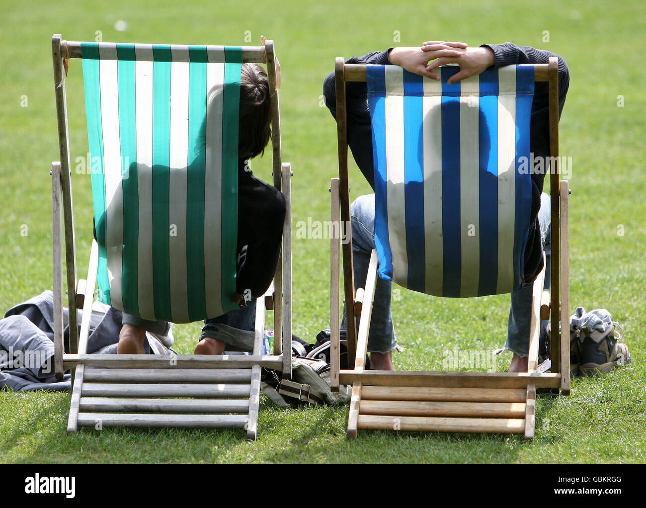 Two people enjoy the warm weather as they sit in the sun in St James's ...
