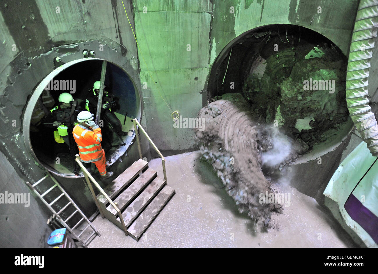 Workers watch the tunnel breakthrough during the completion of the ...