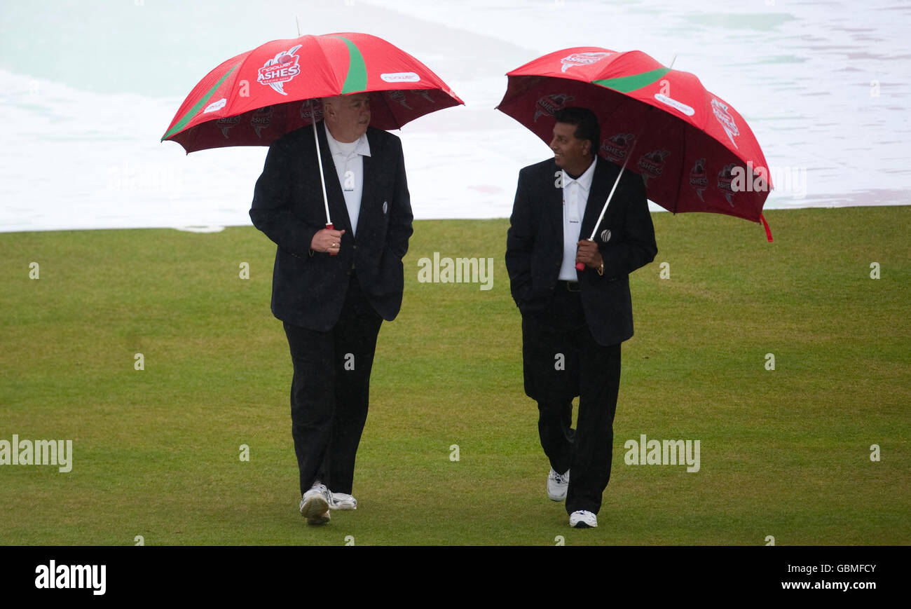 Umpires Steve Davis (left) and Asoka De Silva inspect the field as rain ...